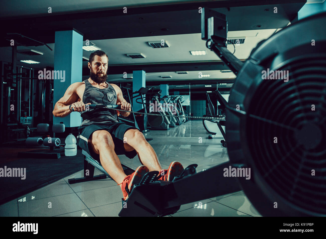 Muscular fit man using rowing machine at gym Stock Photo - Alamy
