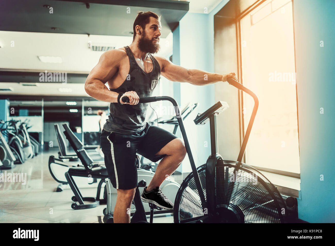 young man using exercise bike at the gym. Fitness male using air bike ...