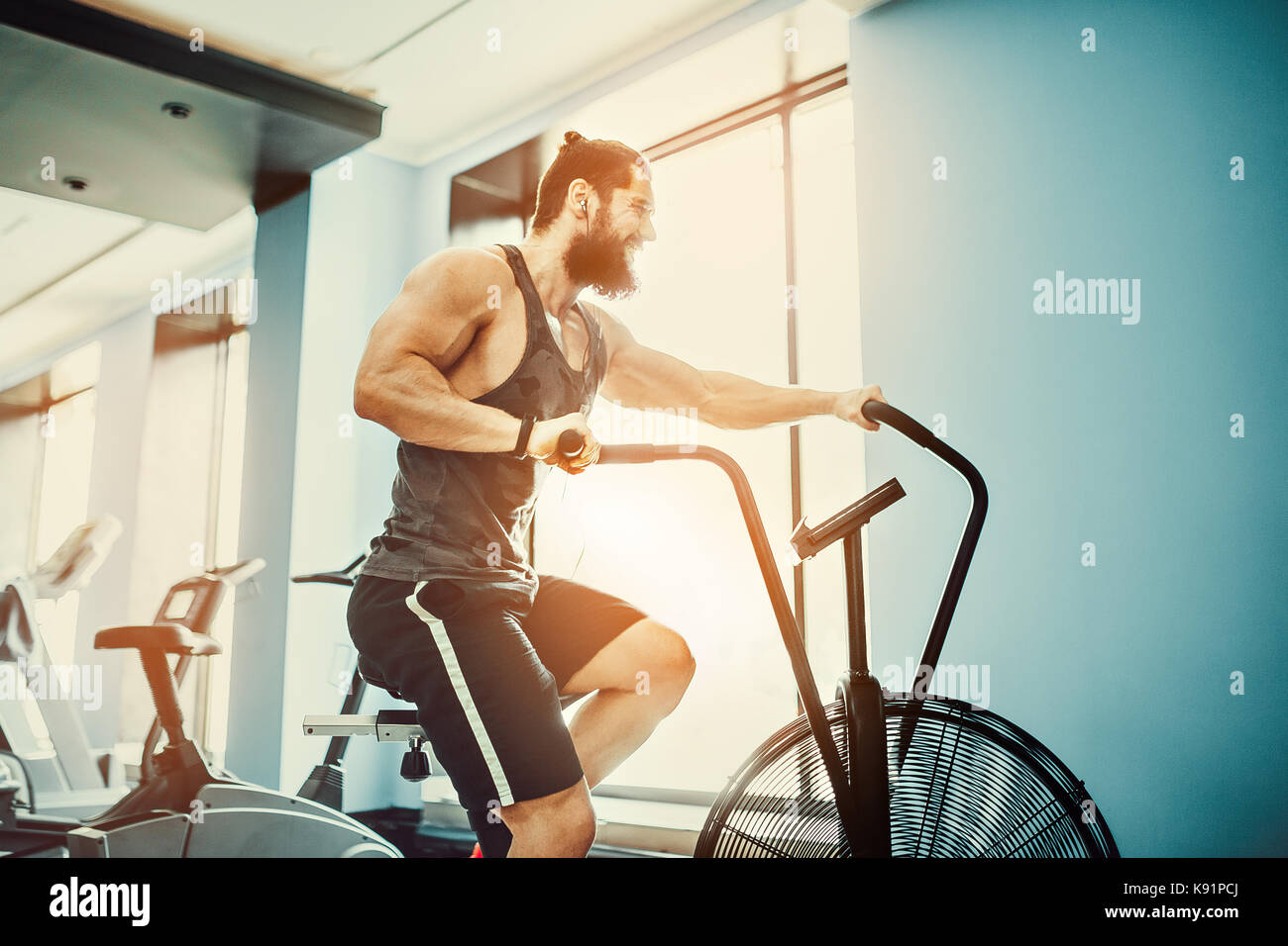 young man using exercise bike at the gym. Fitness male using air bike ...