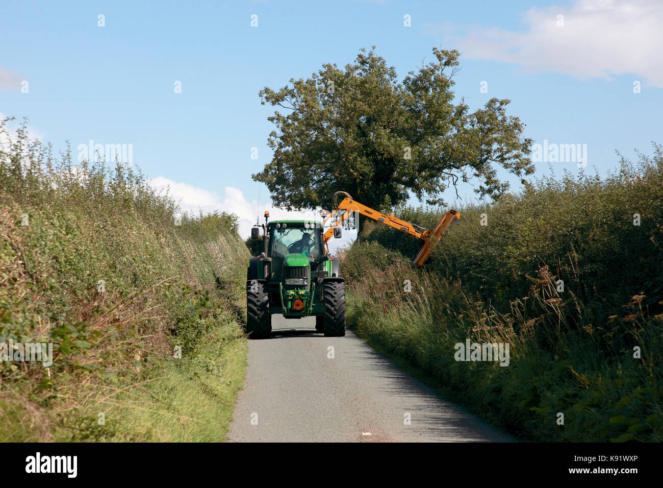 Hedge cutting in a narrow country lane in rural Shropshire, England ...
