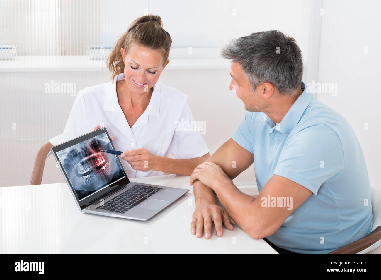 Doctor Showing Dental X-ray On Laptop To Patient In Hospital Stock ...