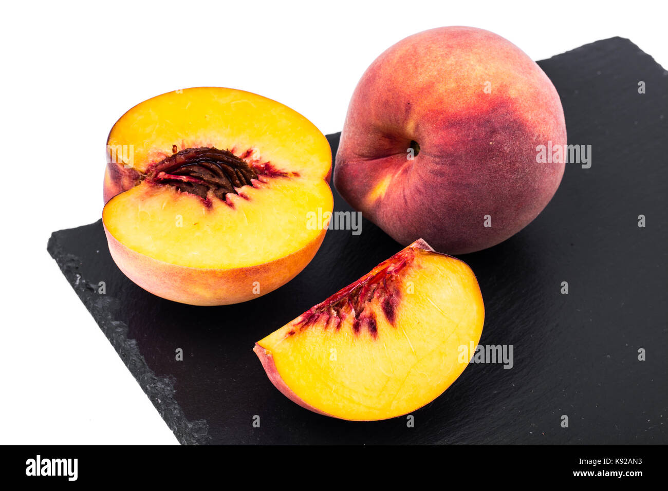 Whole and cut ripe peach on black stone. Studio Photo Stock Photo - Alamy