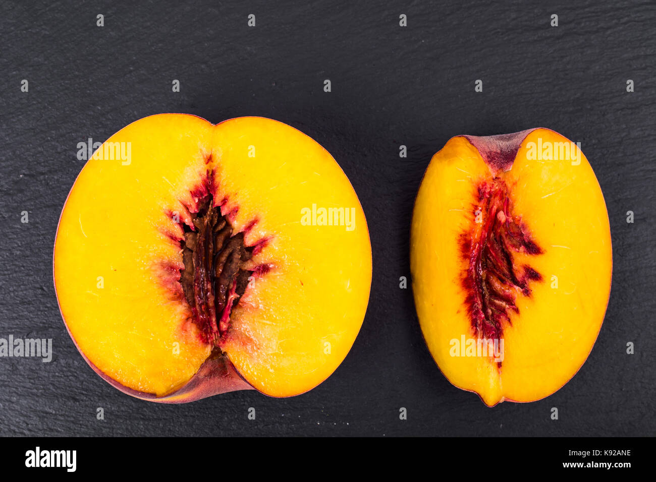 Whole and cut ripe peach on black stone. Studio Photo Stock Photo - Alamy