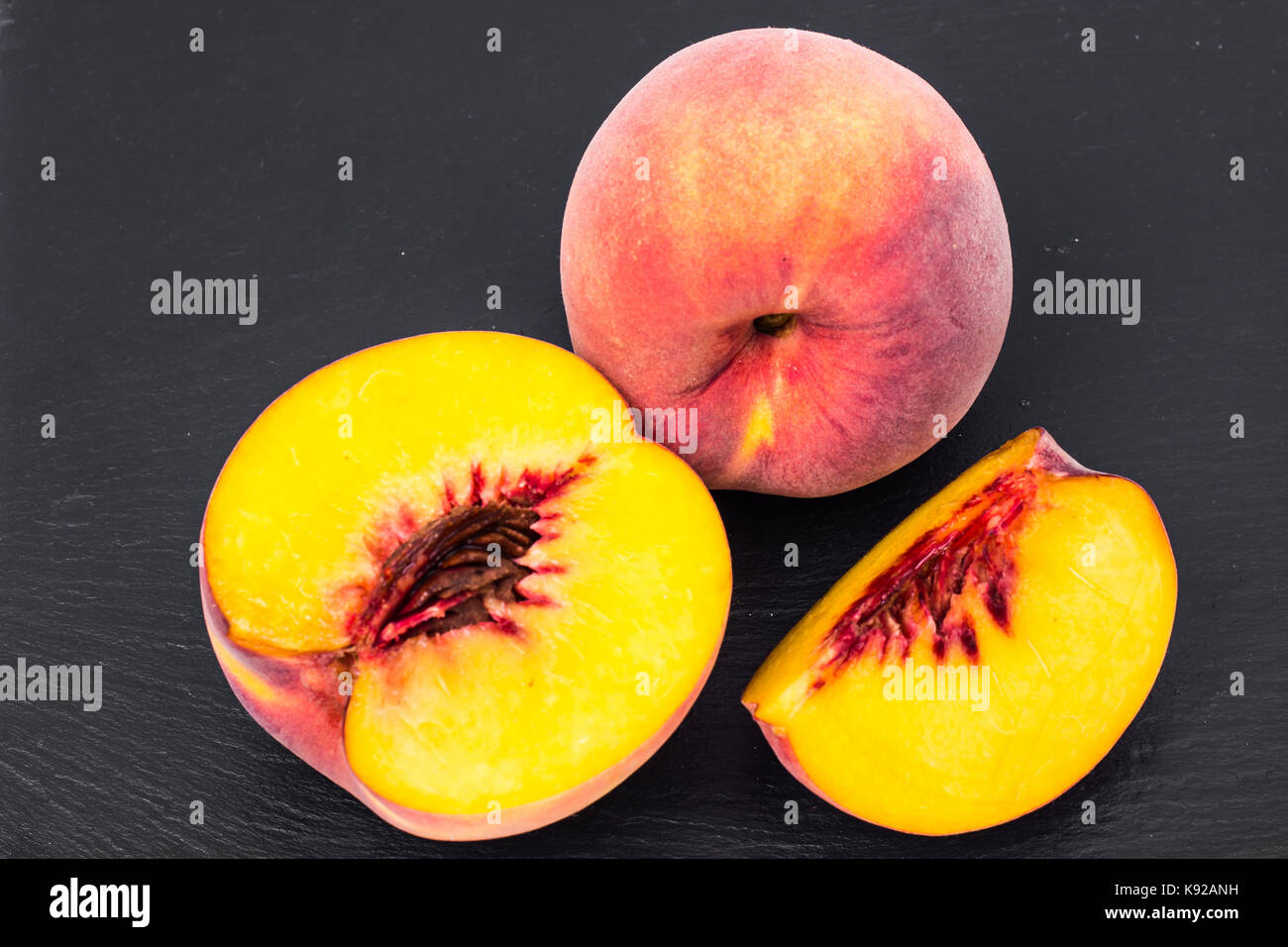 Whole and cut ripe peach on black stone. Studio Photo Stock Photo - Alamy