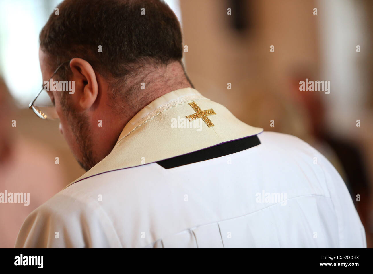 A priest / vicar pictured from behind in a church in Bexhill, East ...