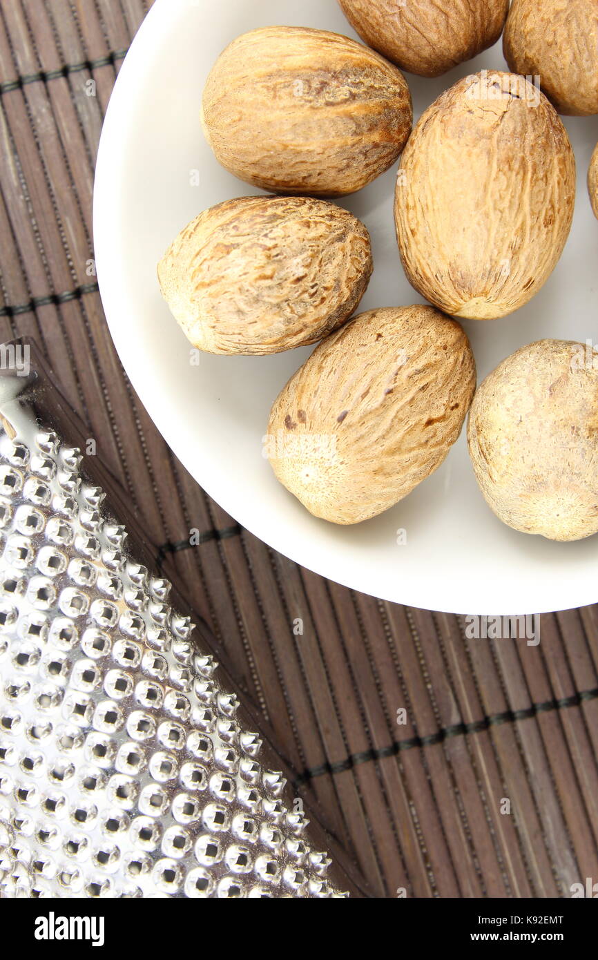 composition of nutmeg seeds in a small white bowl Stock Photo - Alamy