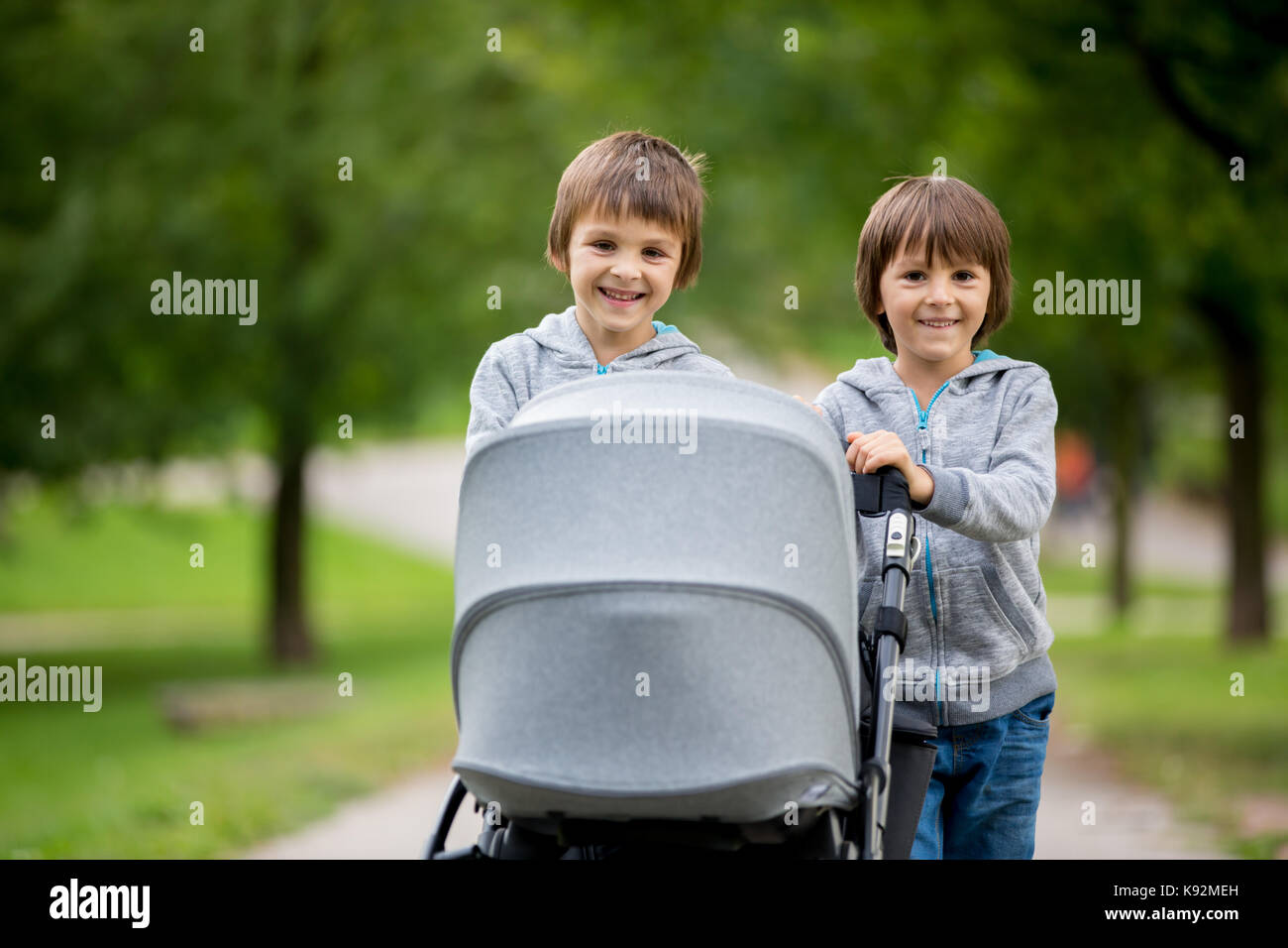 Two children, boys, pushing stroller with little baby in the park Stock ...