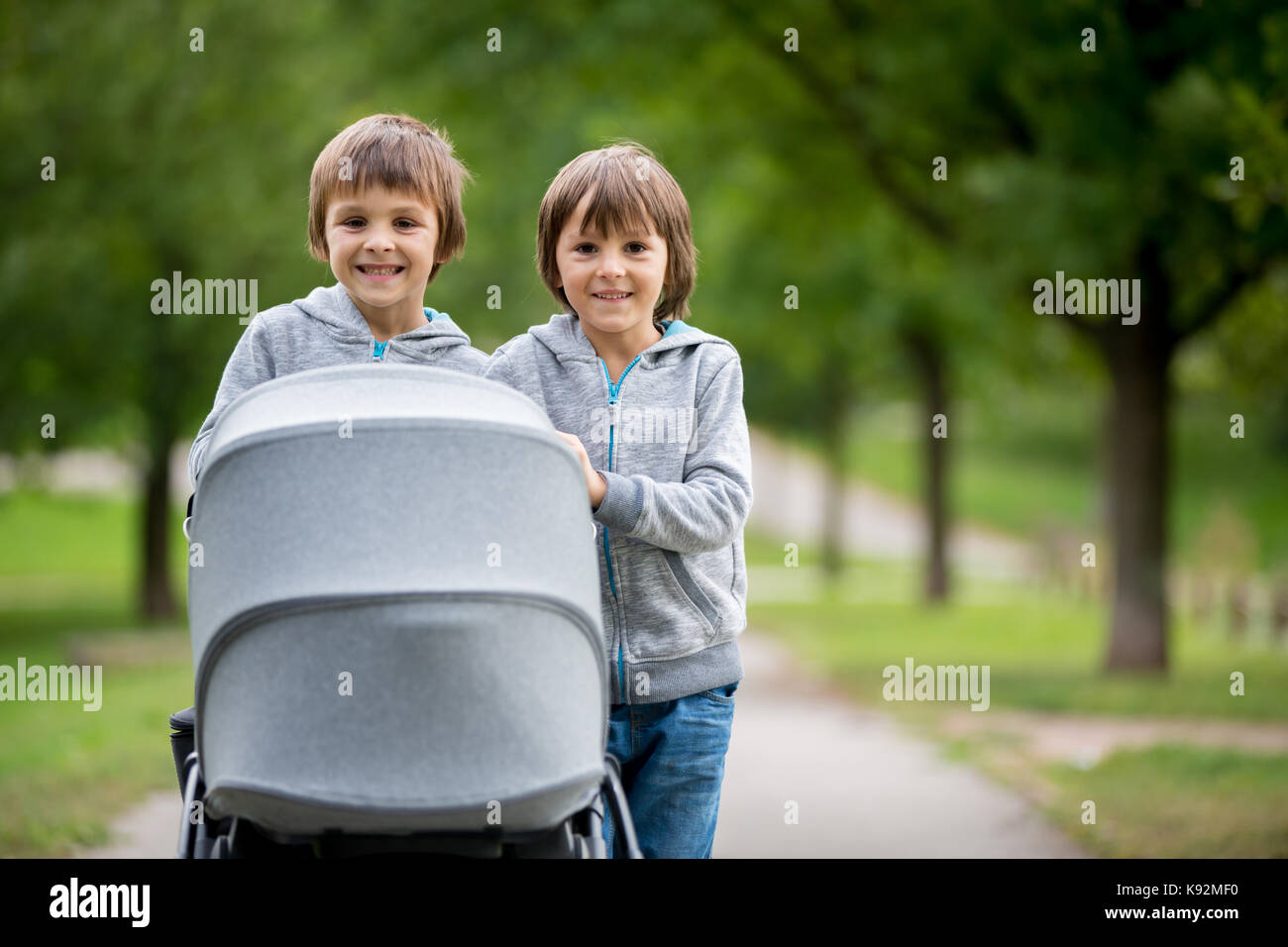Two children, boys, pushing stroller with little baby in the park Stock ...