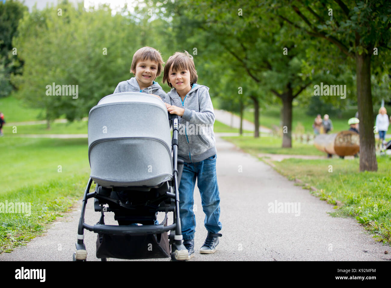 Two children, boys, pushing stroller with little baby in the park Stock ...
