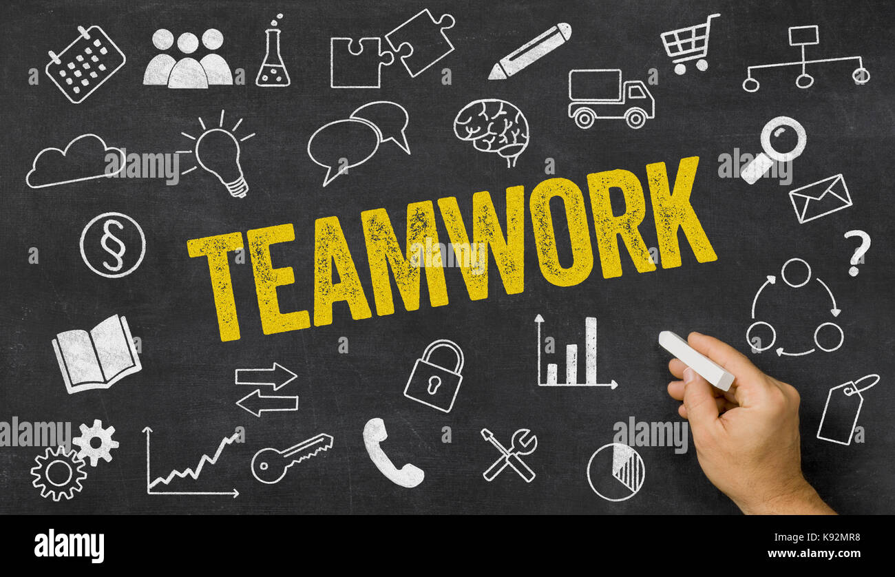 Teamwork written on a blackboard with icons Stock Photo - Alamy