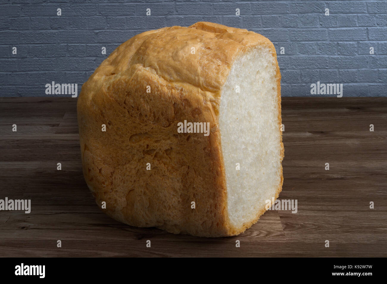 Hand baked and cut loaf of bread on a wooden bench by a grey painted ...