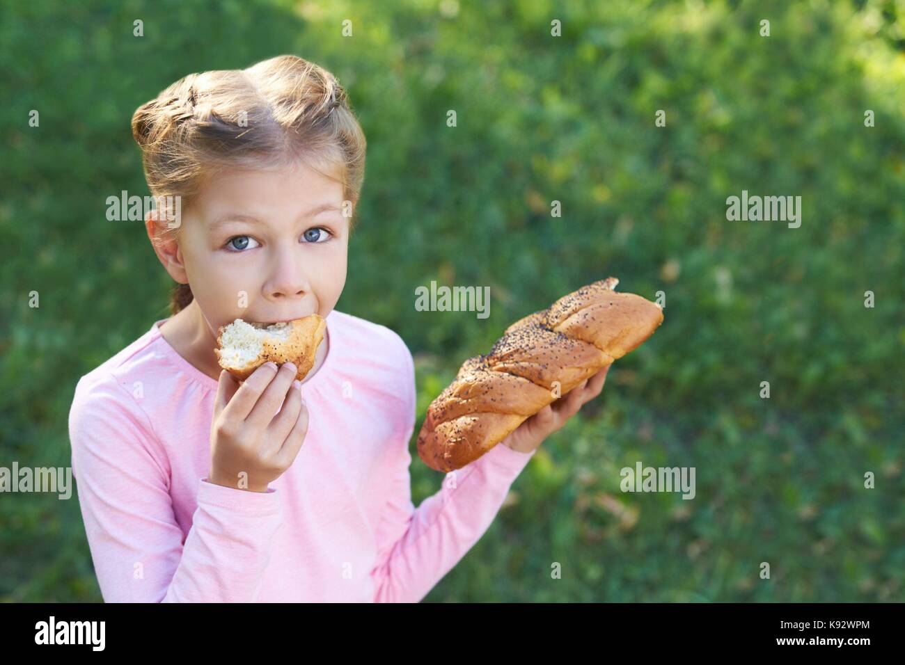 Portrait The girl is eating. Bun Stock Photo - Alamy