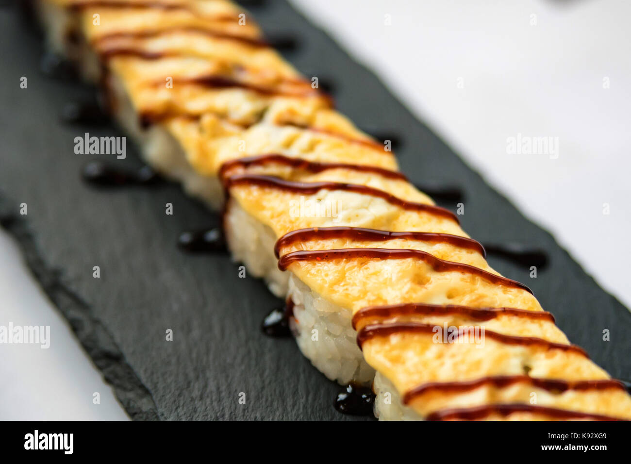 Freshly cooked uncut sushi roll on black board Stock Photo - Alamy