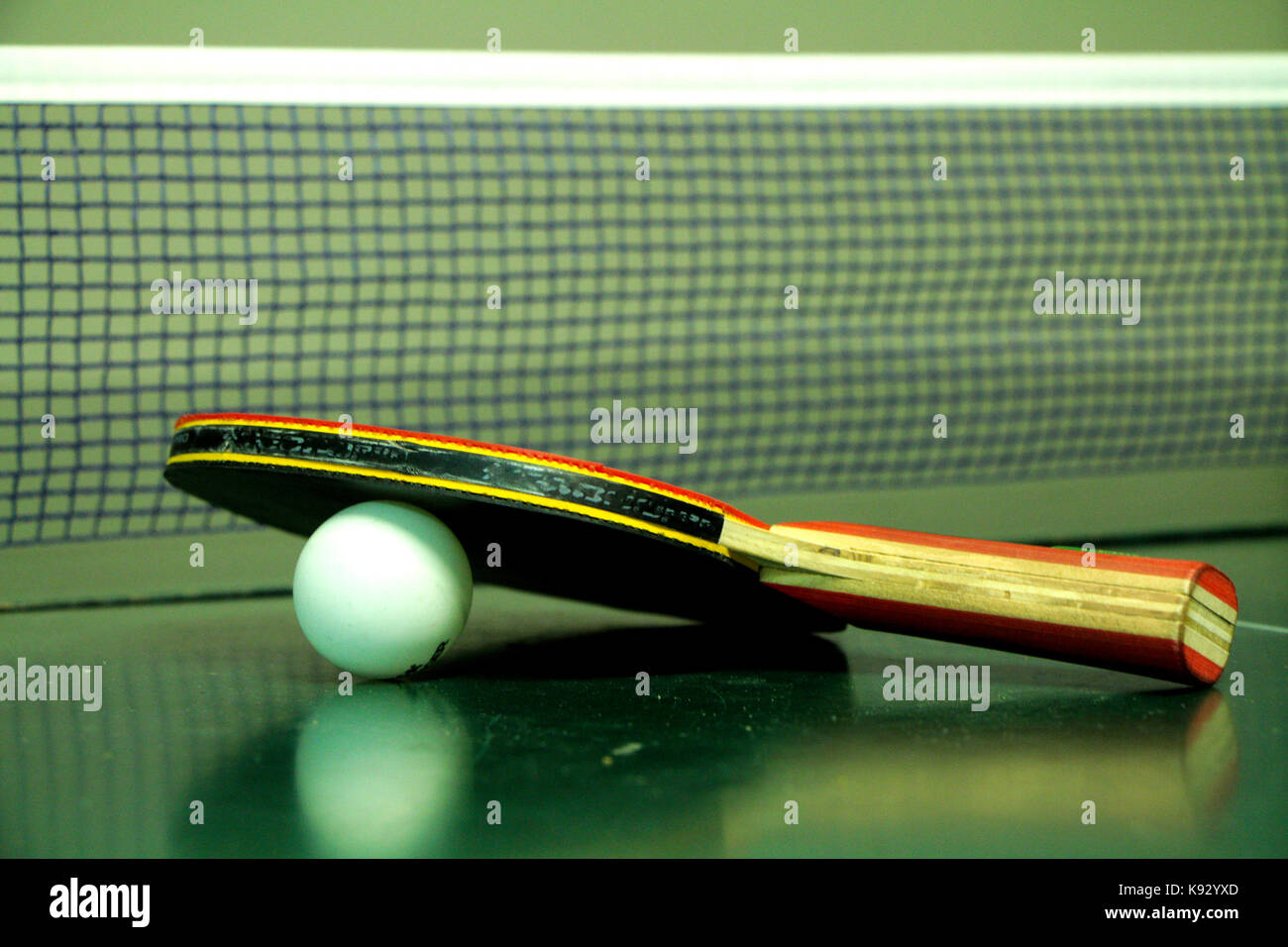 A table tennis or ping pong rackets and ball on a green table with net ...