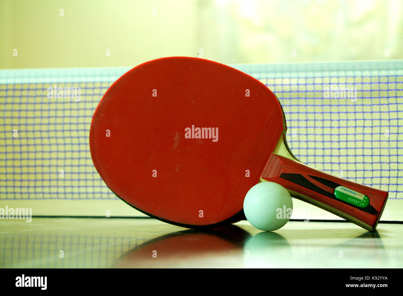 Two red table tennis or ping pong rackets and ball on a green table ...