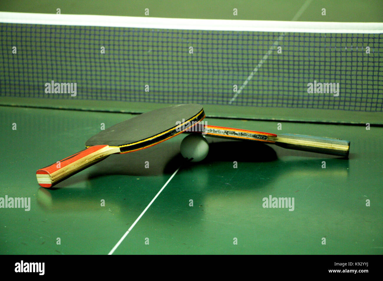Two table tennis or ping pong rackets and ball on a green table with ...