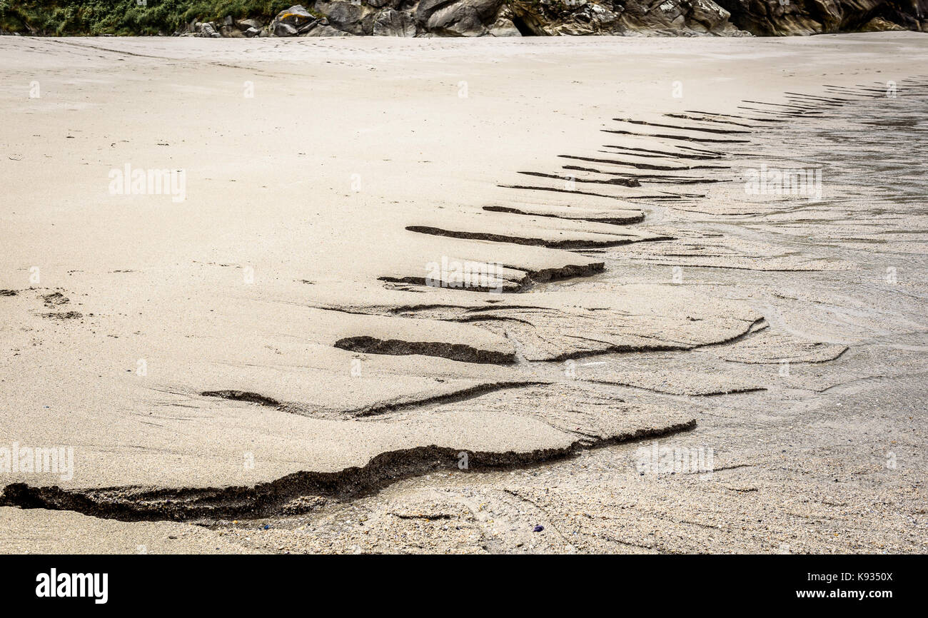 Inflow of fresh water into ocean on sandy beach. The streams of water ...