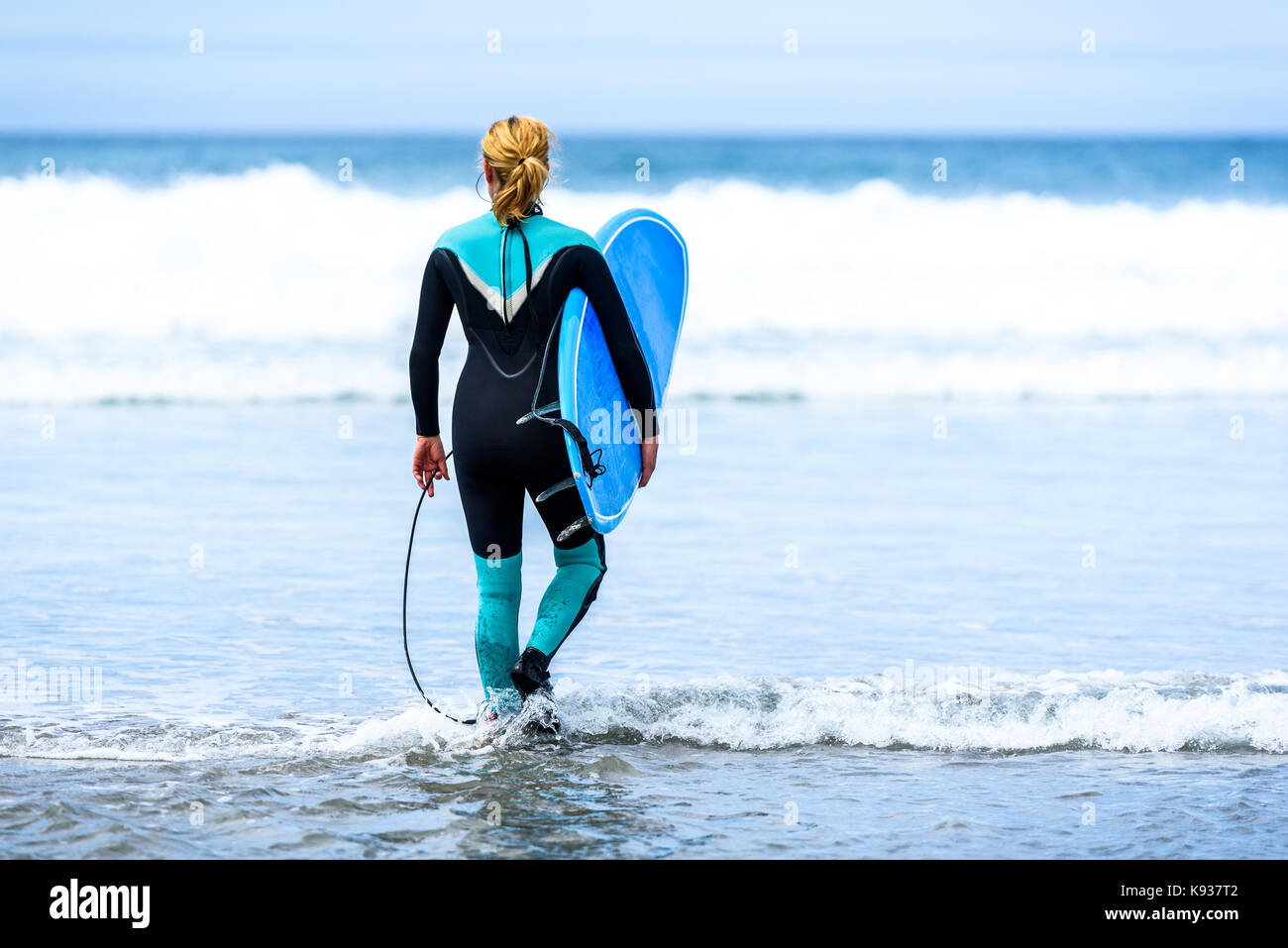 Surfer woman with surfboard is walking and watching the waves. Girl in ...