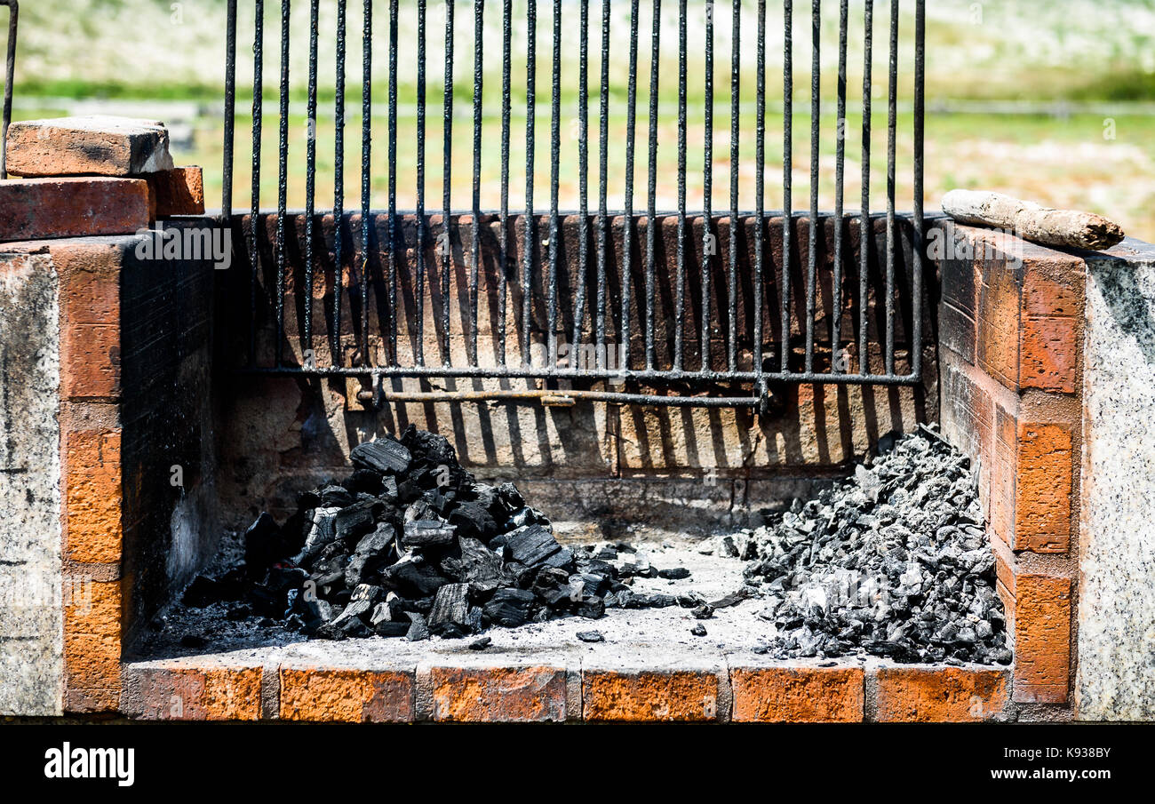 Coal in BBQ barbecue grill on sandy beach on vacation. Making a coal or ...