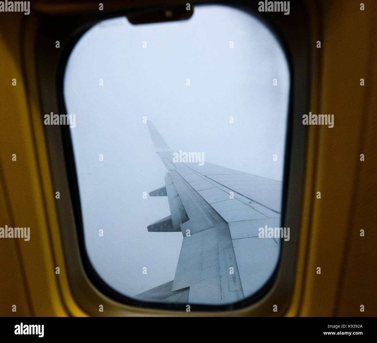 Looking trough window of an aircraft plane wing in fog. View from plane ...