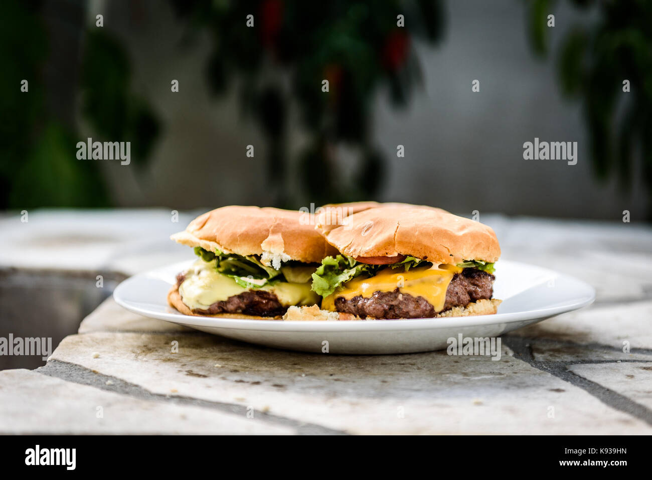 Home made burgers on a plate on stone paved terrace. Delicious home ...