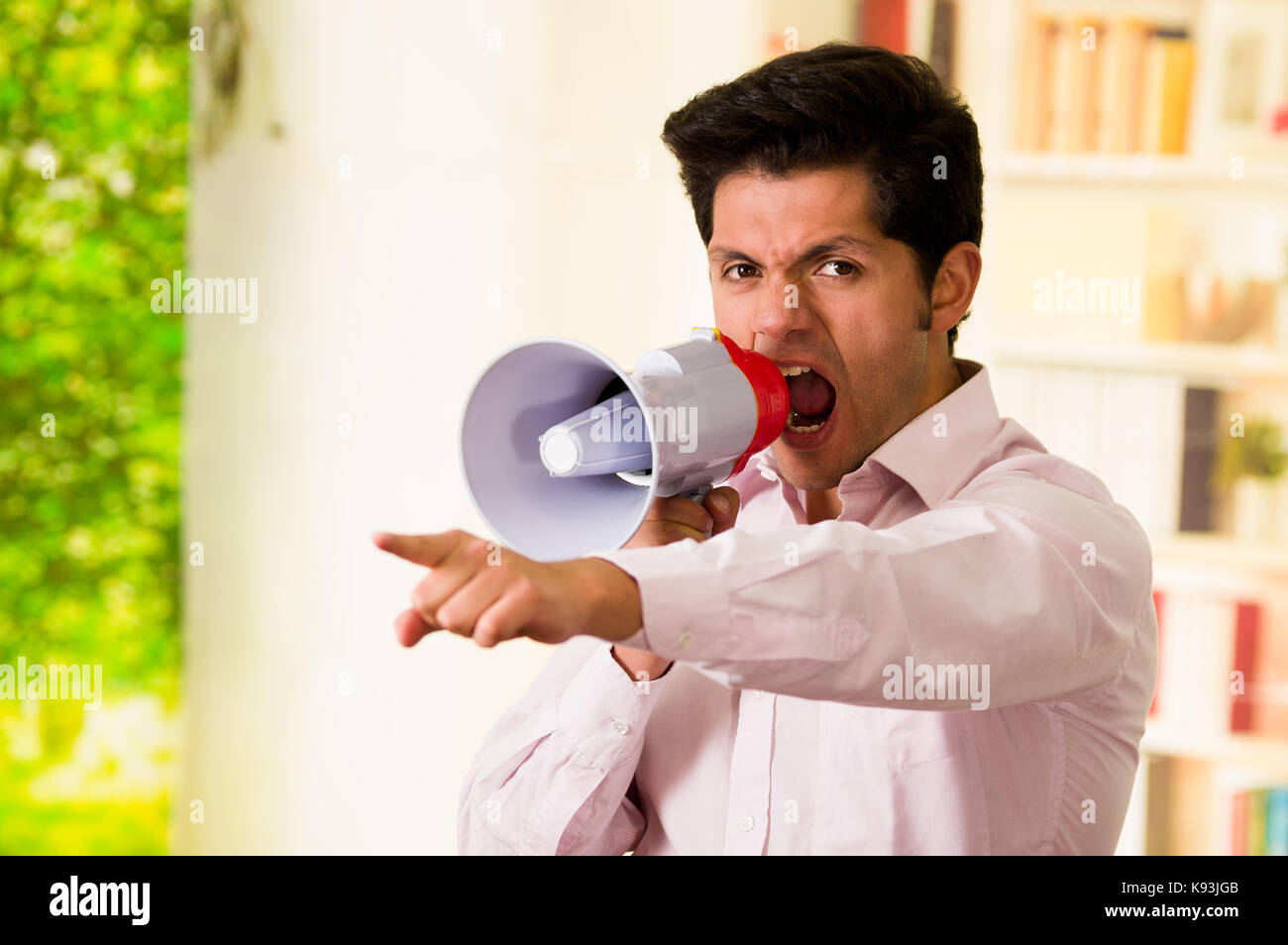 Close up of a handsome man screaming with a megaphone in a blurred ...