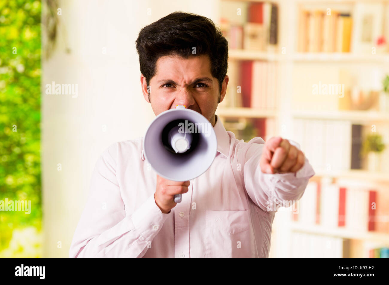 Close up of a handsome man screaming with a megaphone in a blurred ...