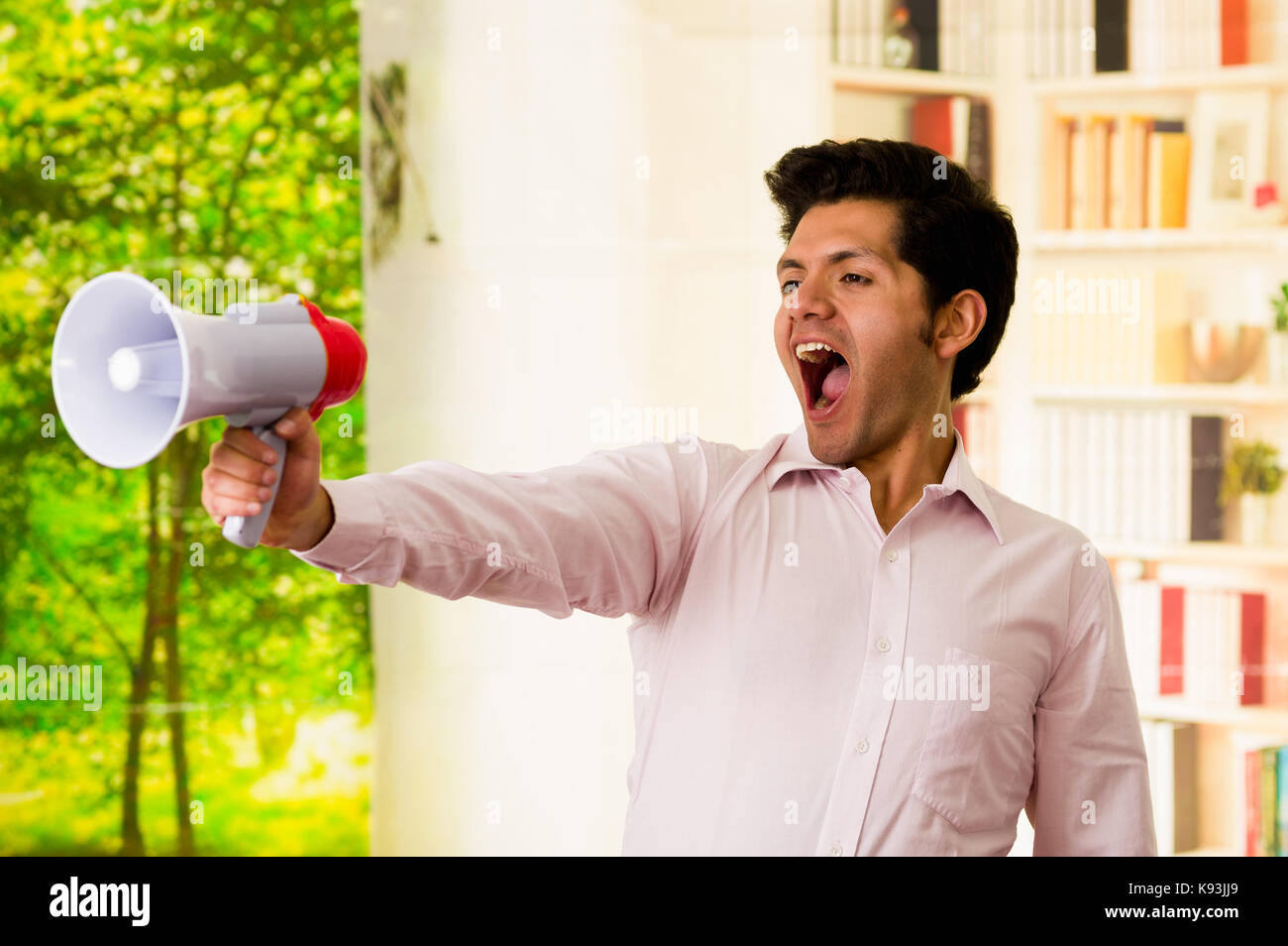Close up of a young man shouting with a megaphone, with his arm ...