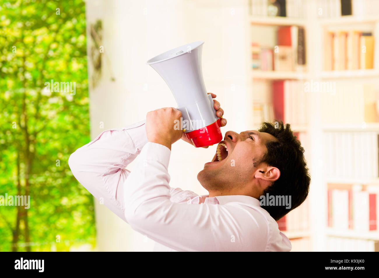 Close up of a handsome man screaming with a megaphone, pointing to the ...