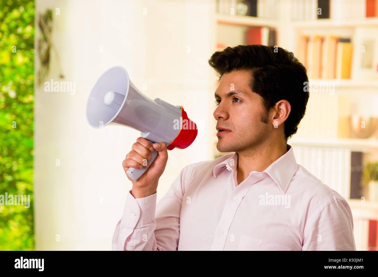 Close up of a handsome serious man holding a megaphone in his hand in a ...