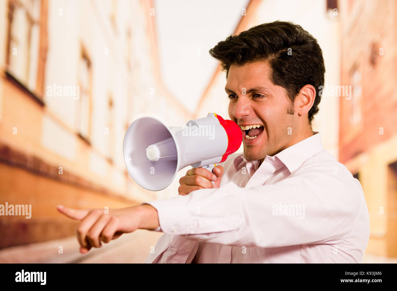 Close up of a handsome man screaming with a megaphone, pointing his ...