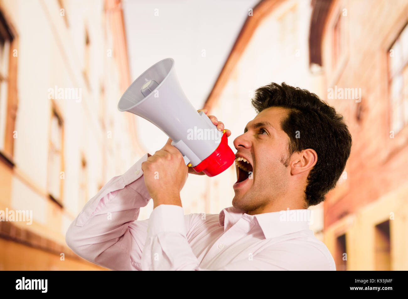 Close up of a handsome man screaming with a megaphone, pointing to the ...