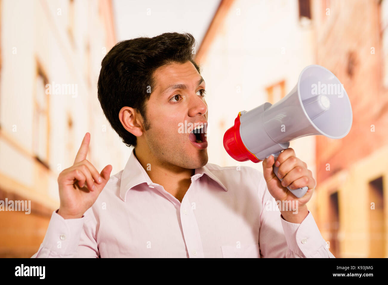Close up of a handsome man screaming with a megaphone, doing a signal ...