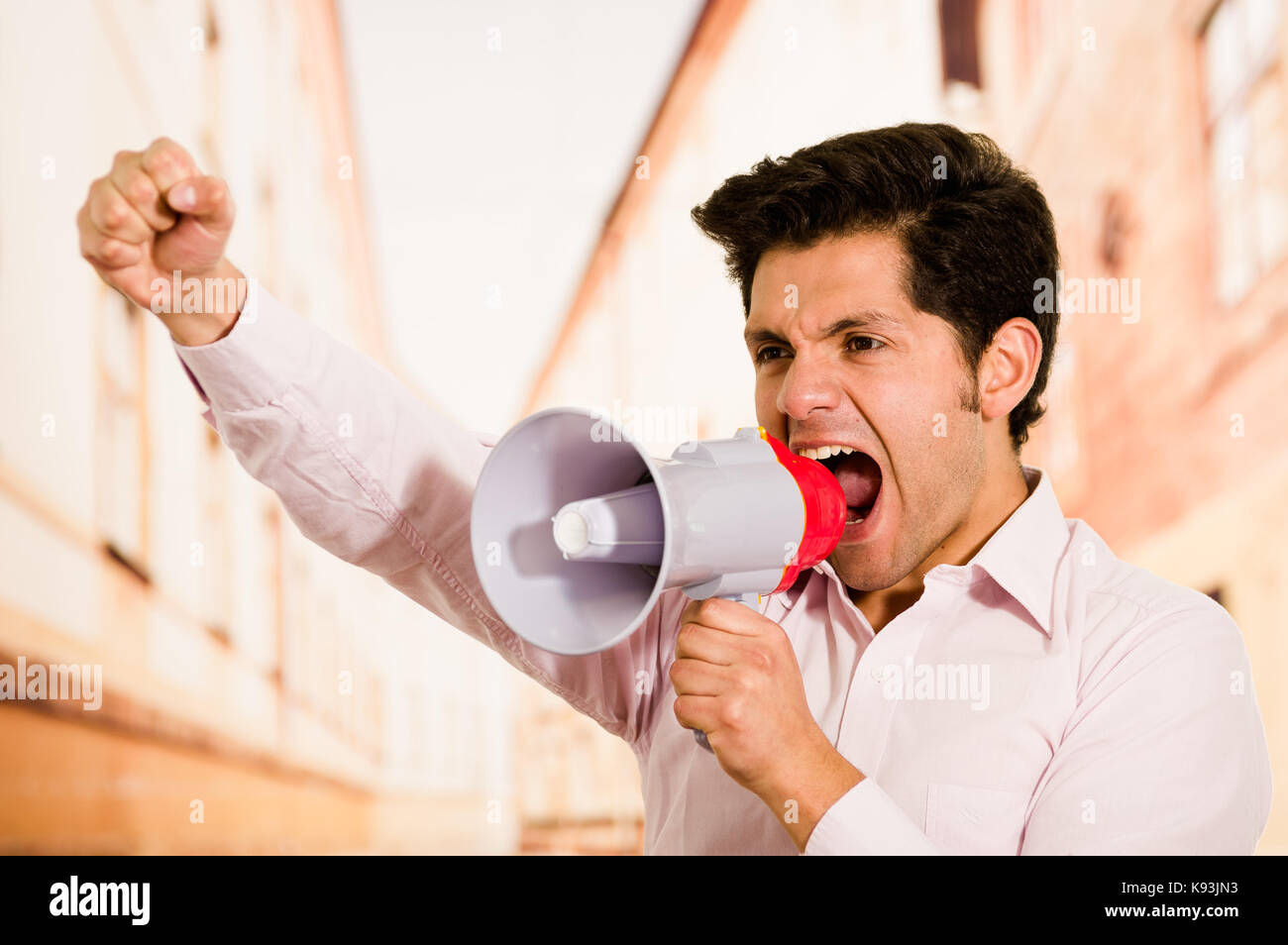 Close up of a handsome man screaming with a megaphone in a blurred ...