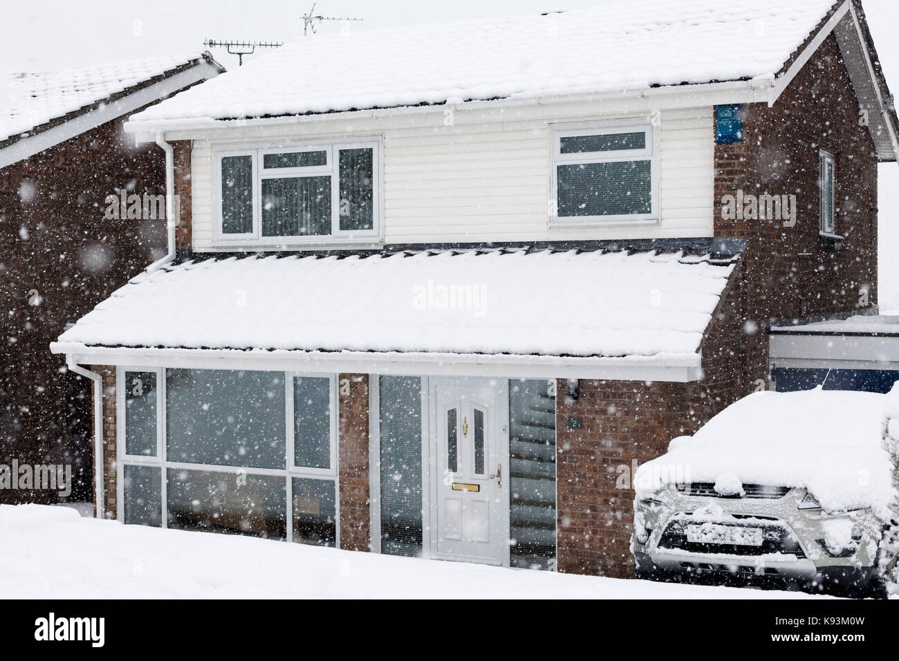 A home in England covered in freshly falling snow during a winter storm ...