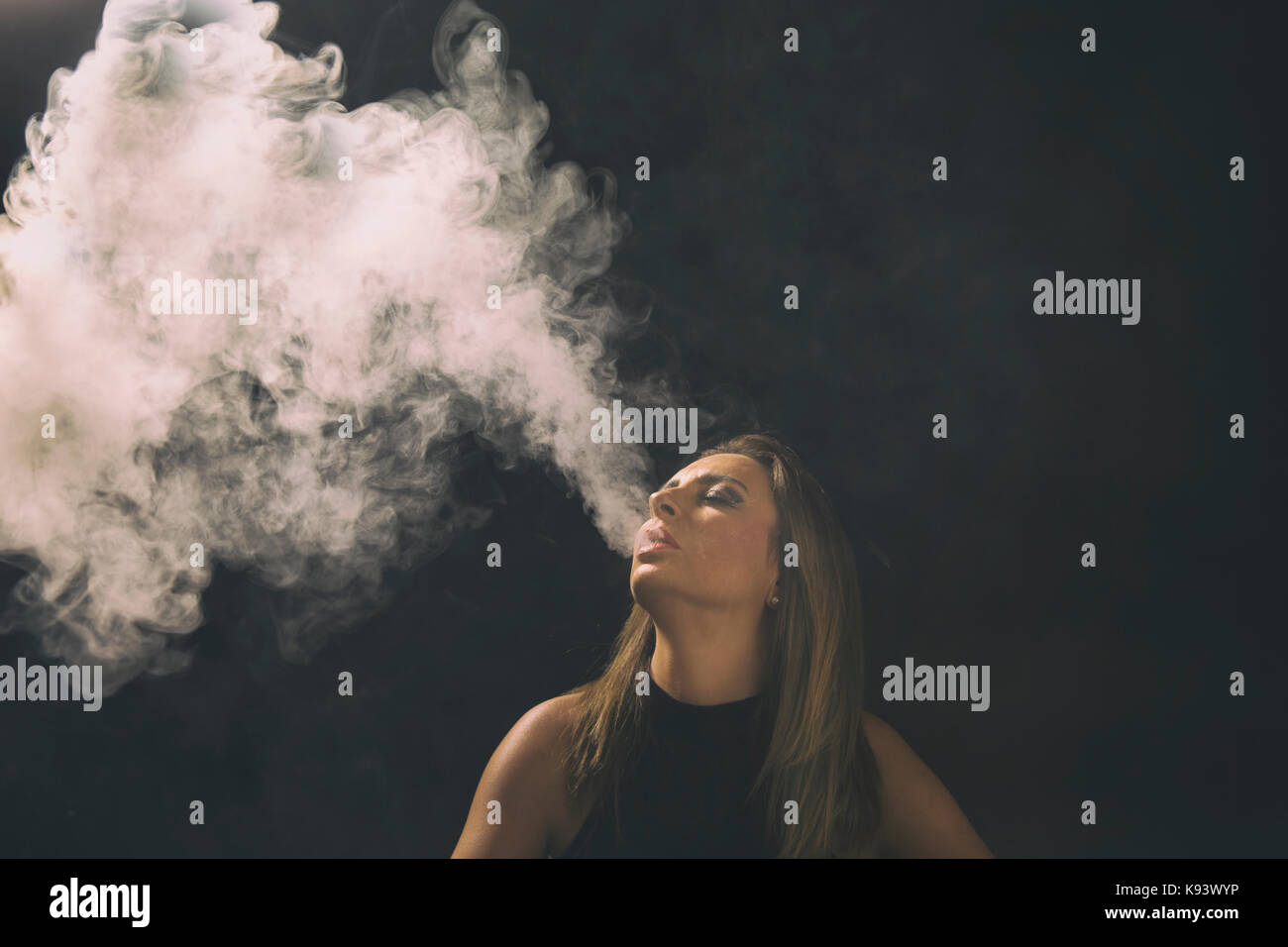Young woman vaping. Studio shot. Black background Stock Photo - Alamy