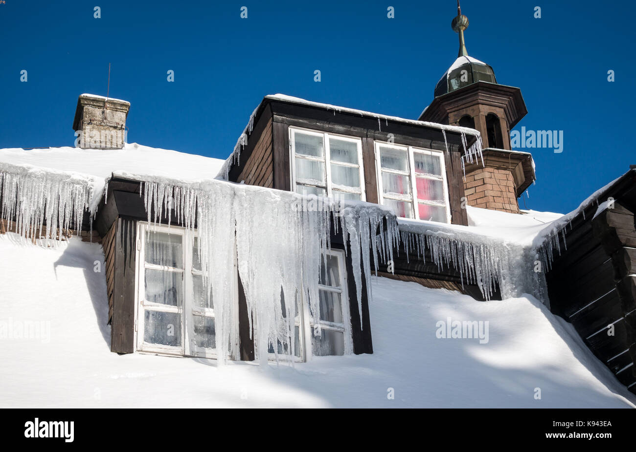 Icicles on roof with windows and clear blue sky Stock Photo - Alamy