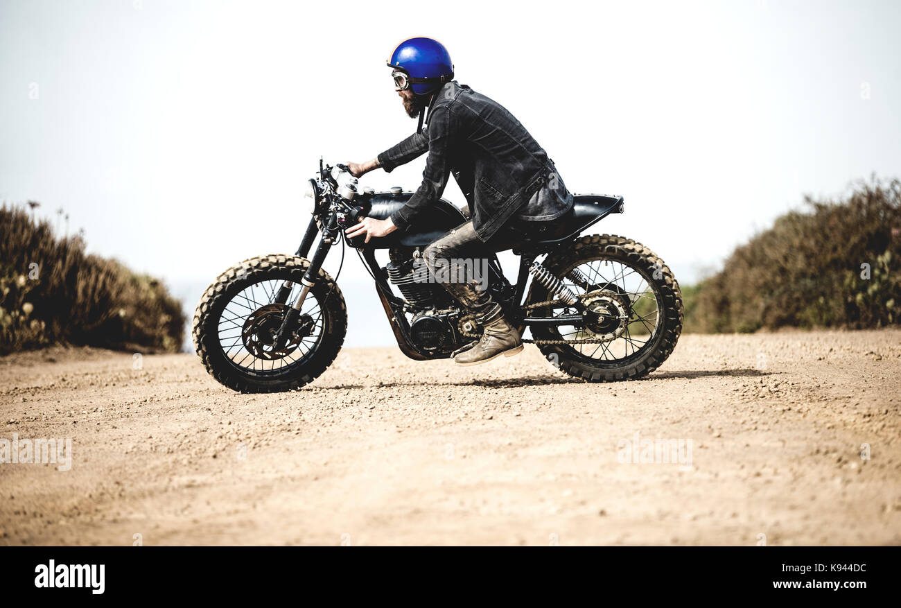 Side view of man wearing blue open face crash helmet and goggles riding ...