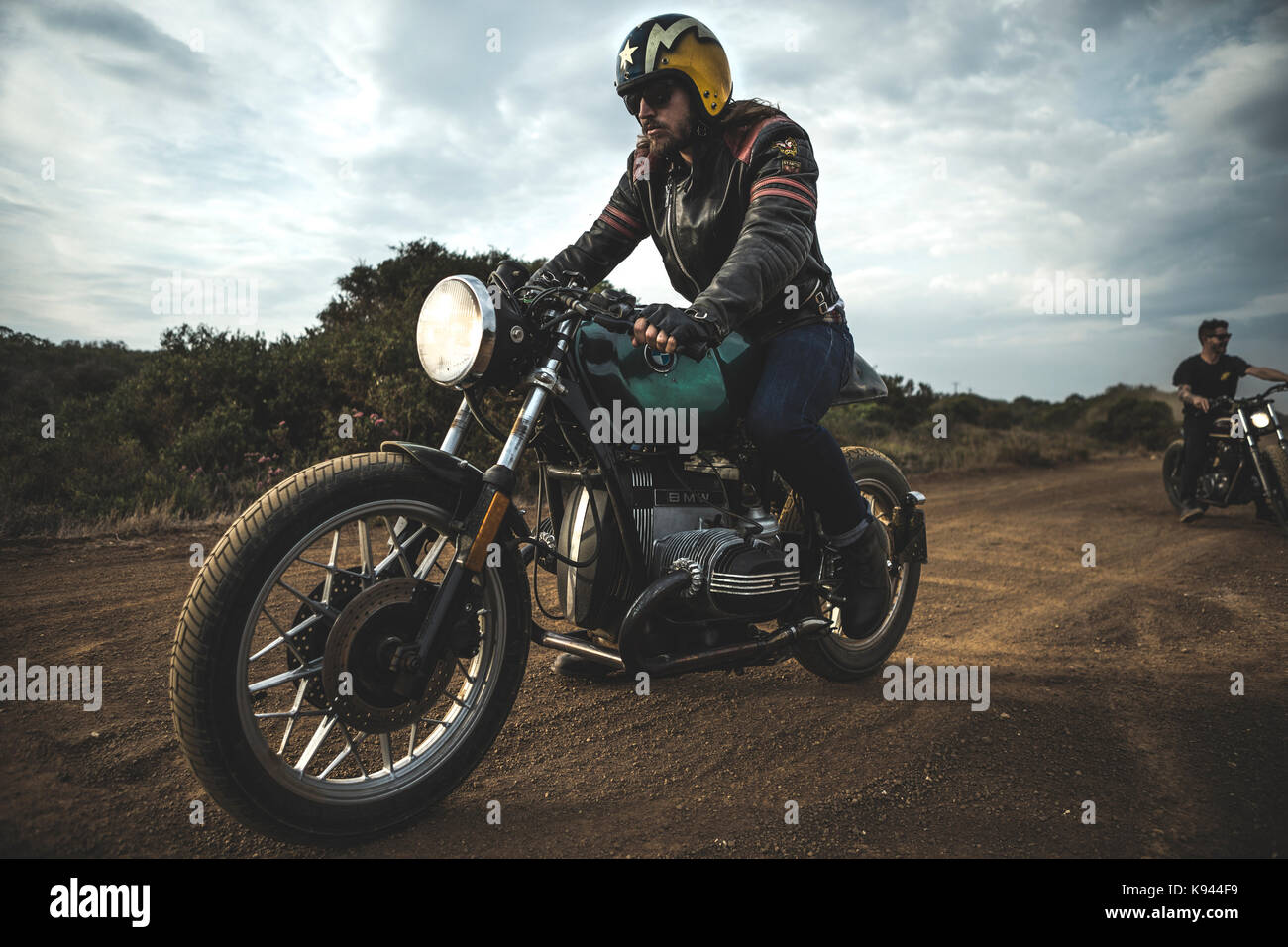 Man wearing open face crash helmet and sunglasses riding cafe racer ...