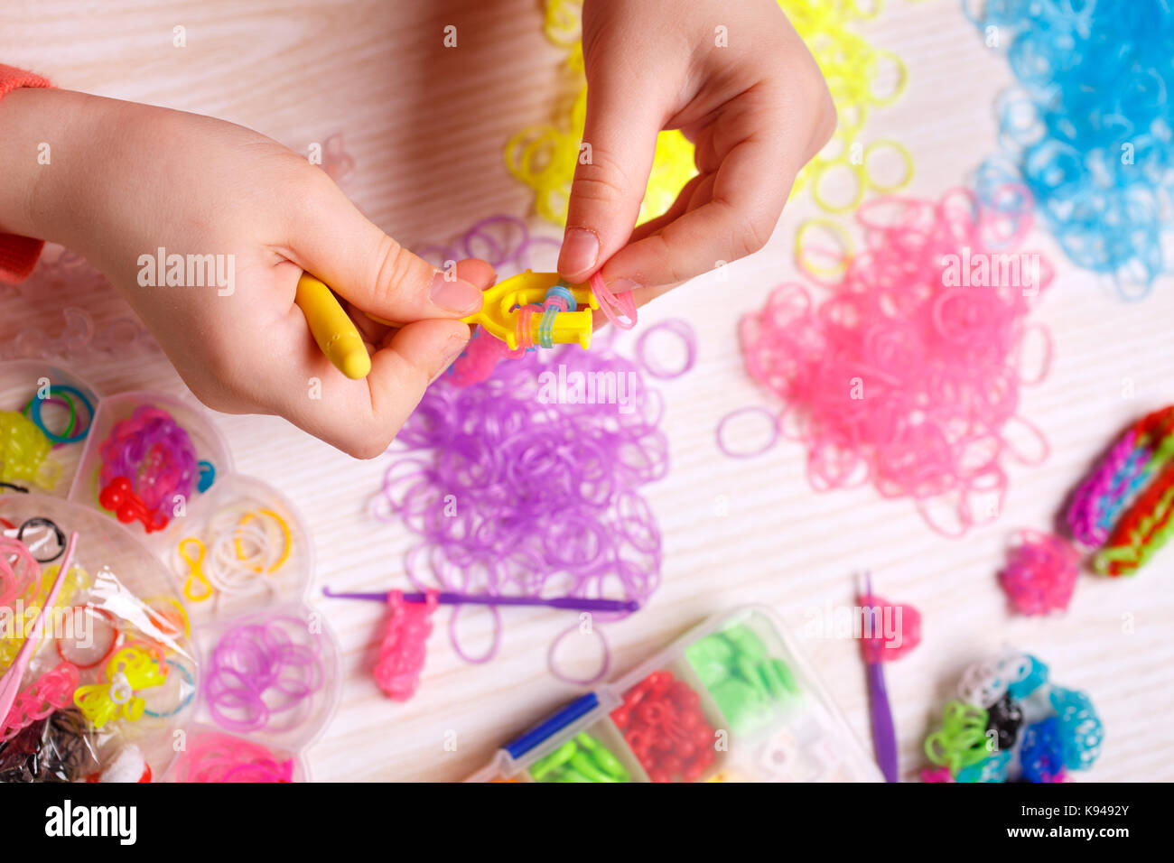 hands weaving of rubber band bracelet, closeup, wooden background Stock ...