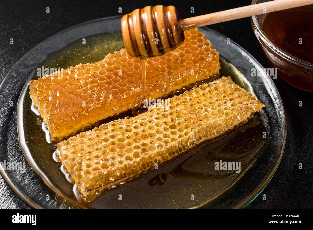 Honey and honeycomb on black dish Stock Photo - Alamy