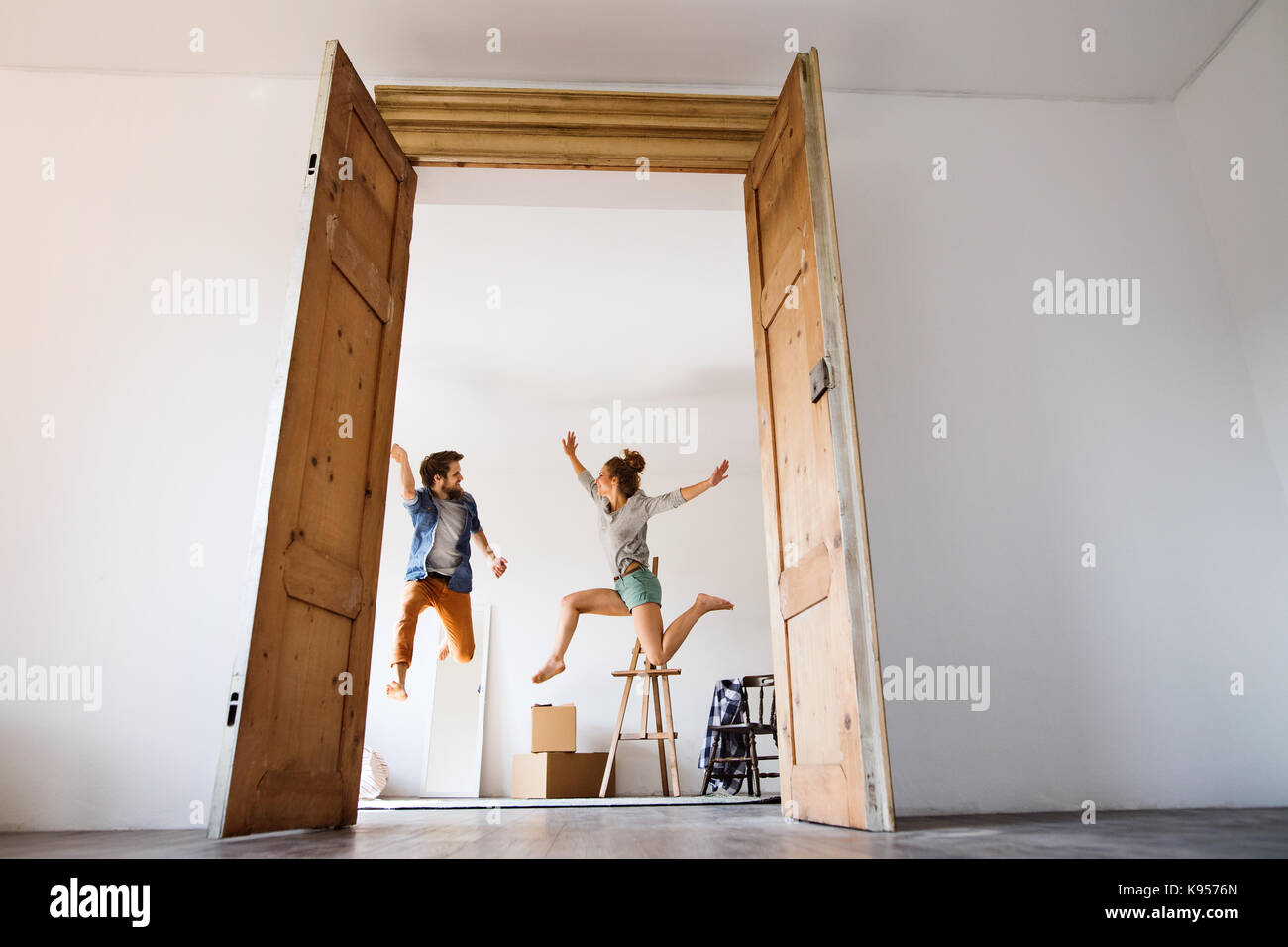 Young married couple moving in a new house, jumping up high Stock Photo ...