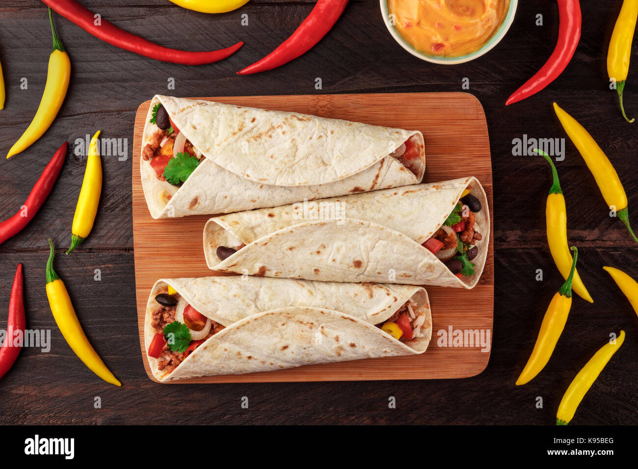 Mexican burritos with cheese salsa, and chili peppers Stock Photo - Alamy