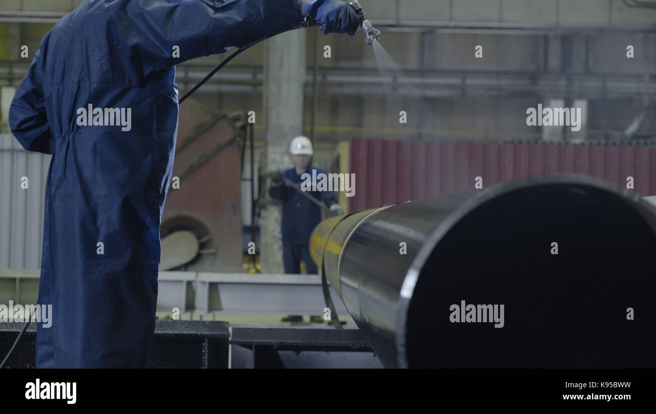 Man paints pipe atomizer. Mens hand paint the pipes on the plant ...