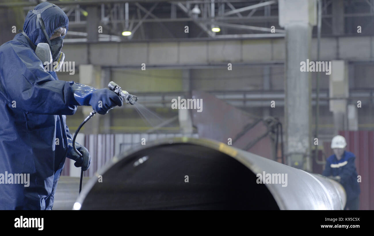 Male holding spray gun and painted steel. Man paints pipe atomizer ...