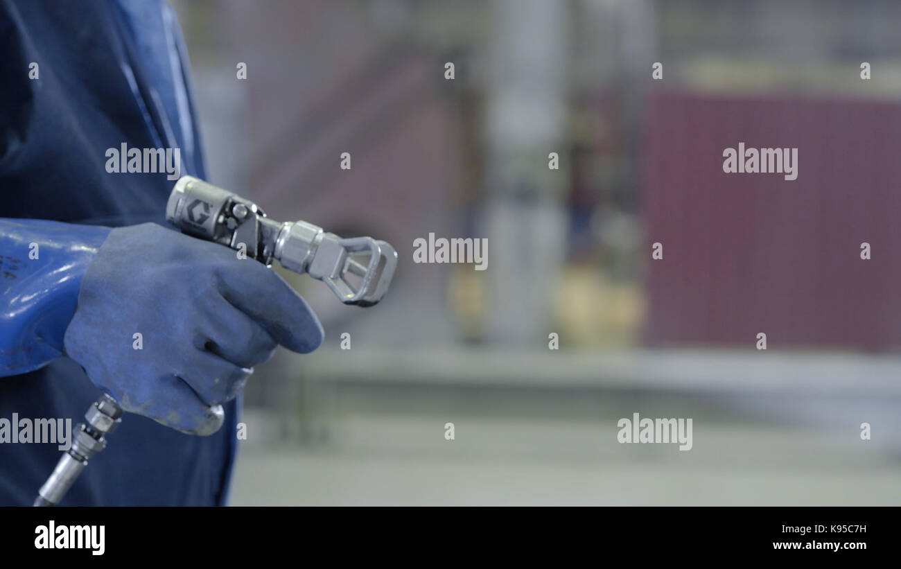 Arm hand holding industrial size spray gun used for industrial painting ...