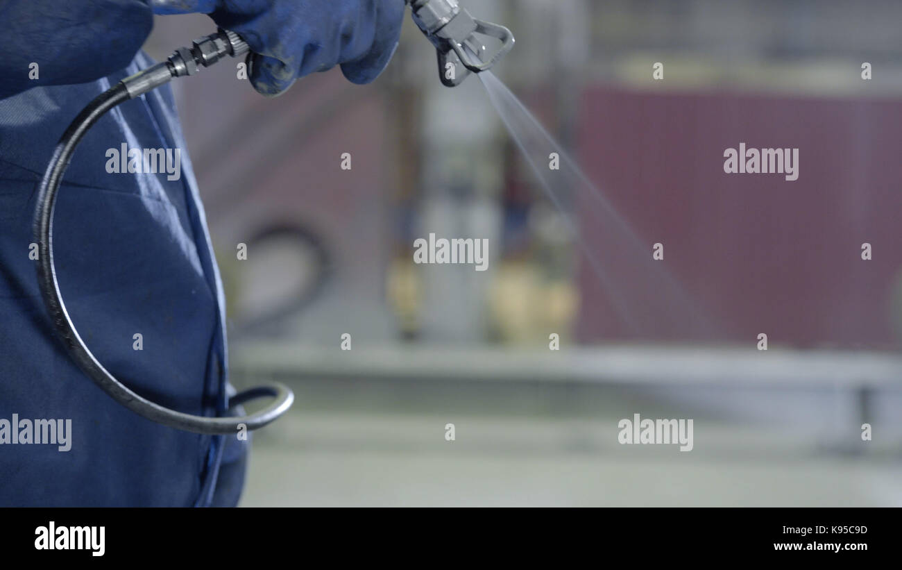 Arm hand holding industrial size spray gun used for industrial painting ...