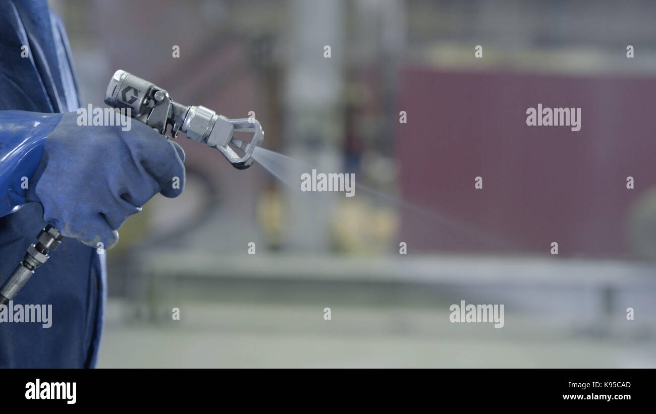 Arm hand holding industrial size spray gun used for industrial painting ...