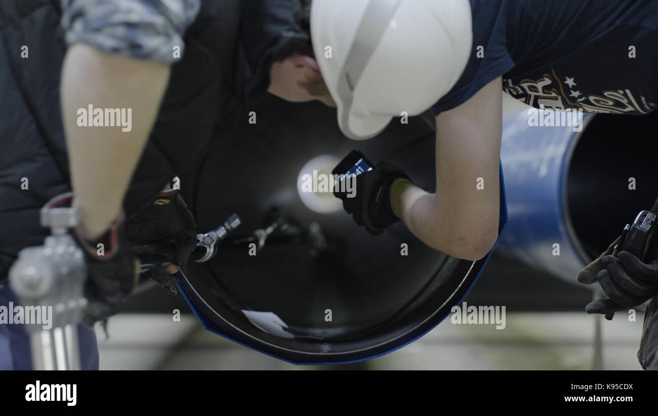 Working on tubular production. Men look inside the pipe Stock Photo - Alamy