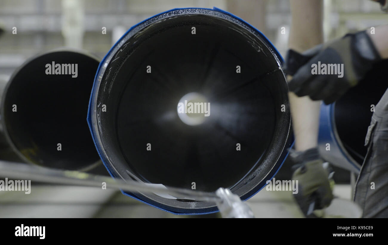 Working on tubular production. Men look inside the pipe Stock Photo - Alamy